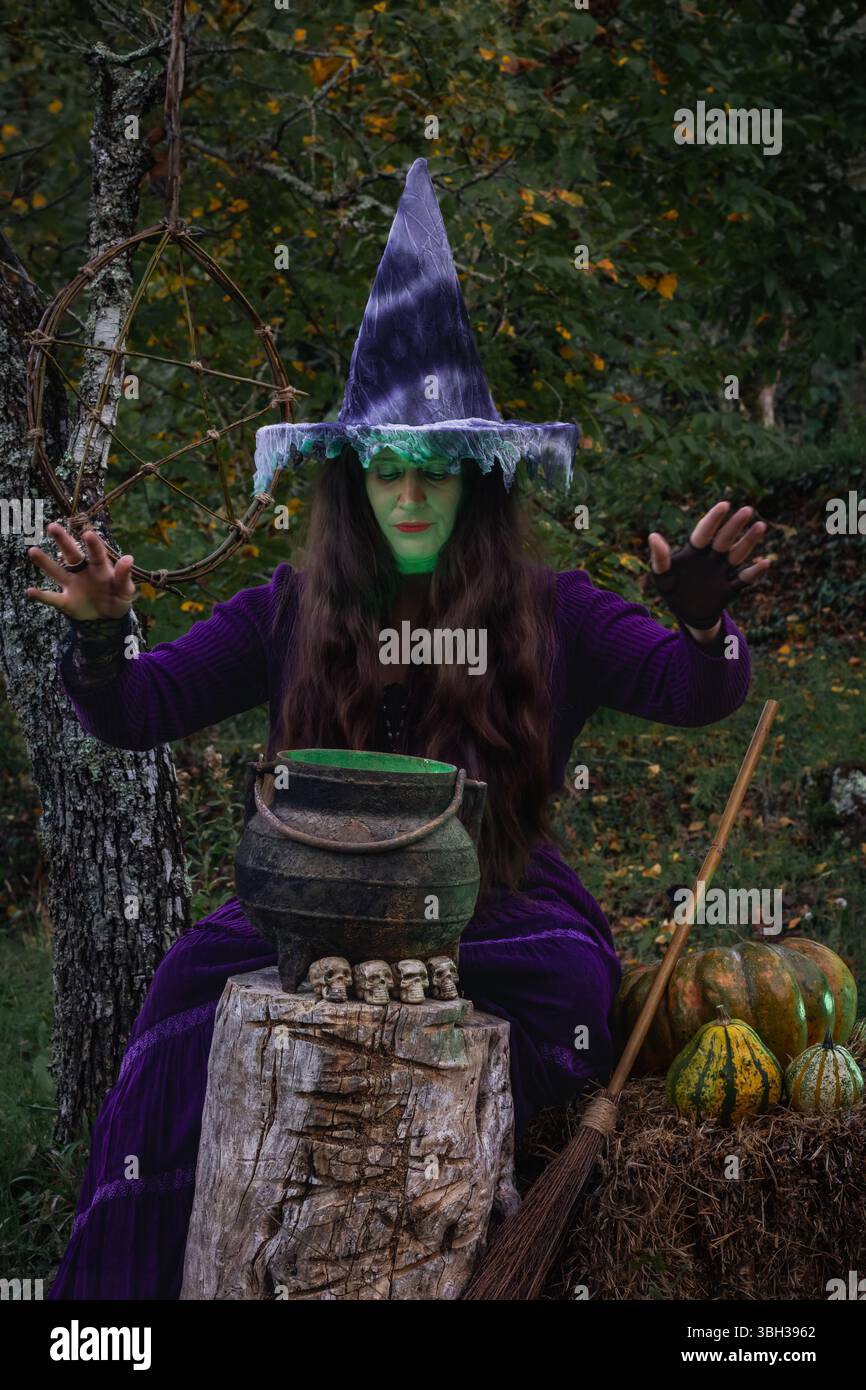 Purple clothed witch, casting spells over a green glowing cauldron in ...