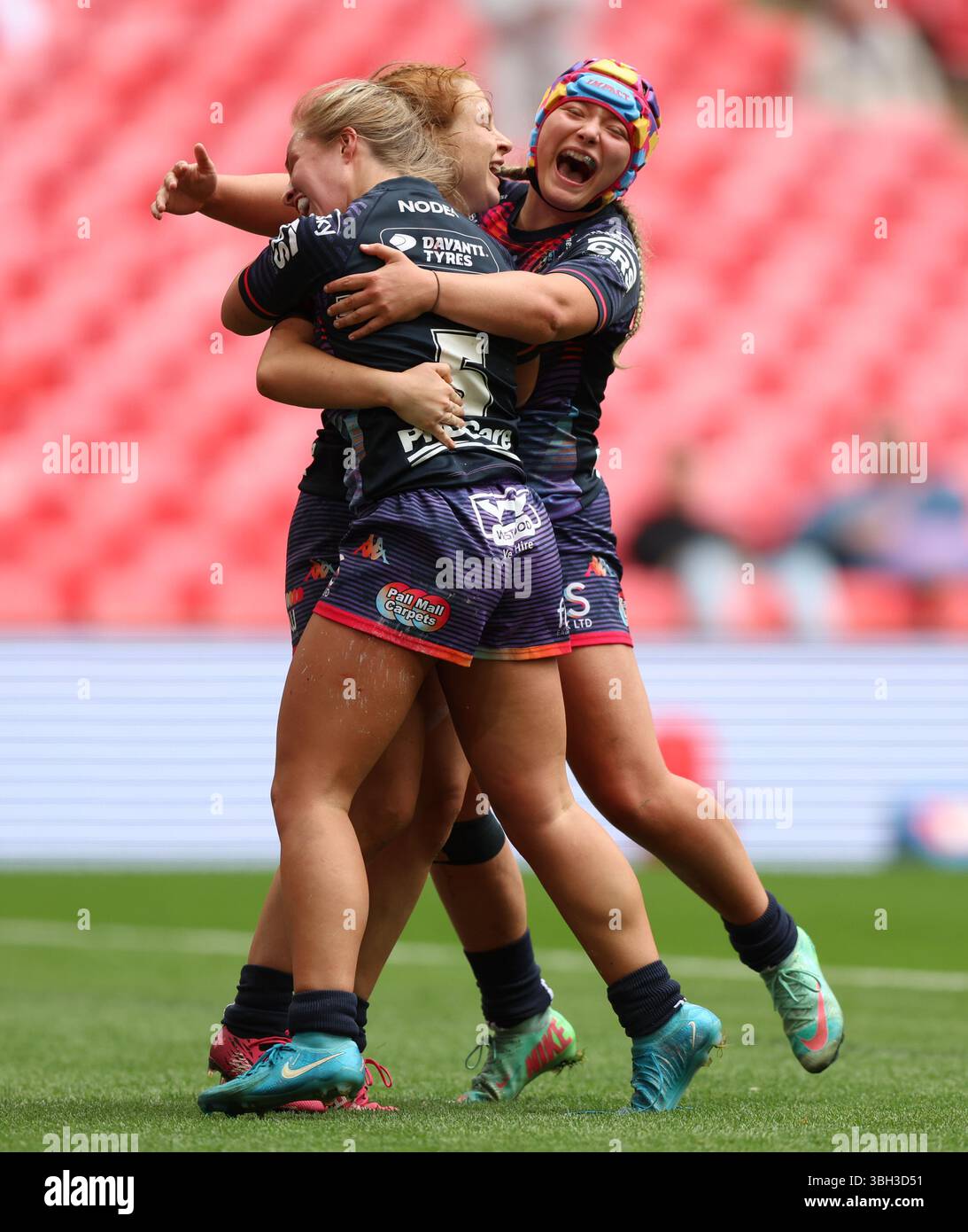 Wigan Warriors' Grace Banks (centre) celebrates scoring a try with team ...
