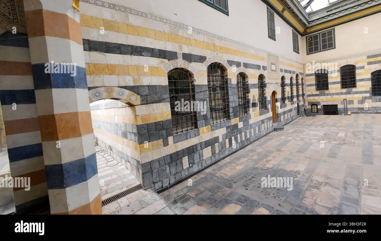 A historic courtyard with striped stone walls and arched windows ...