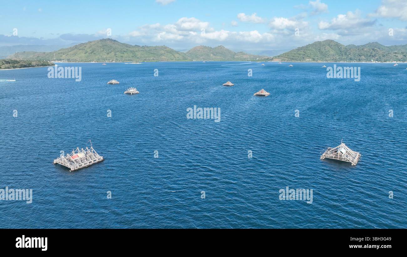 Traditional bamboo fishing platforms float on the open sea with green ...