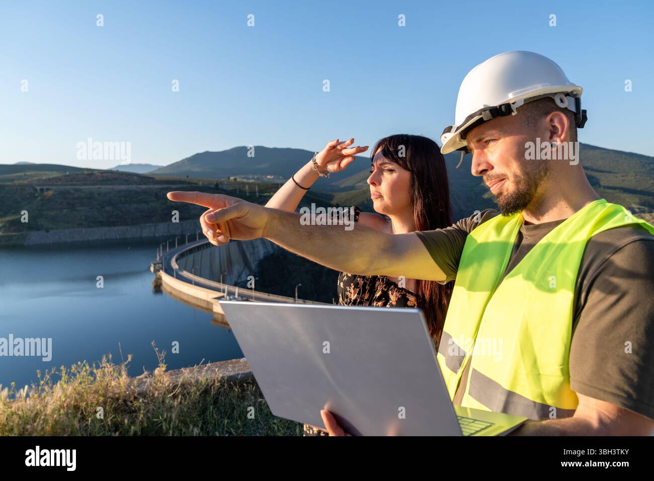 Engineers pointing at dam using laptop for inspection Stock Photo - Alamy