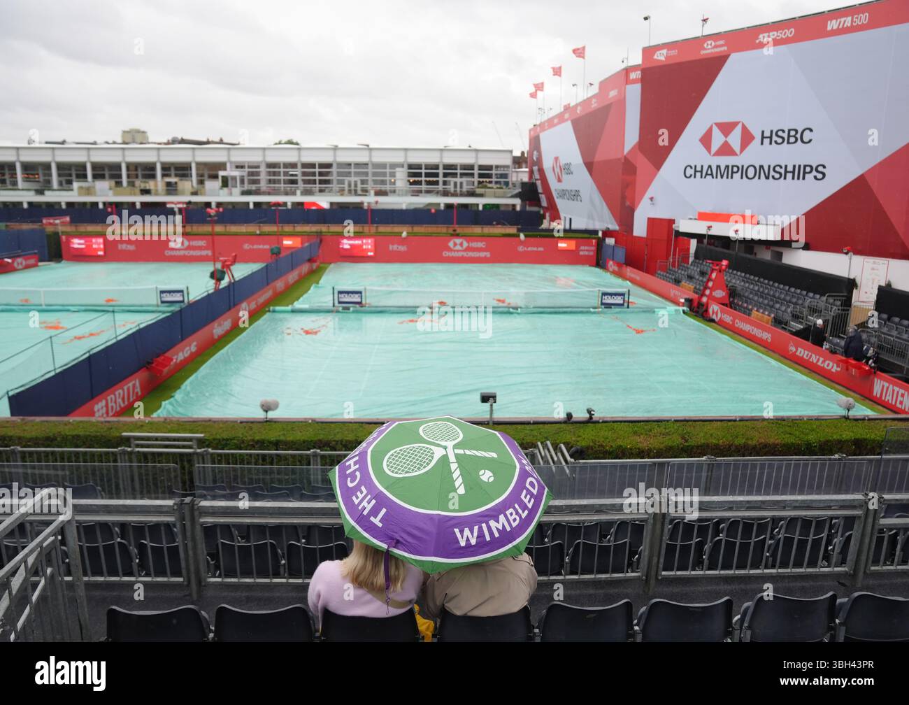 Spectators wait for play to resume on day one of the HSBC Championships ...