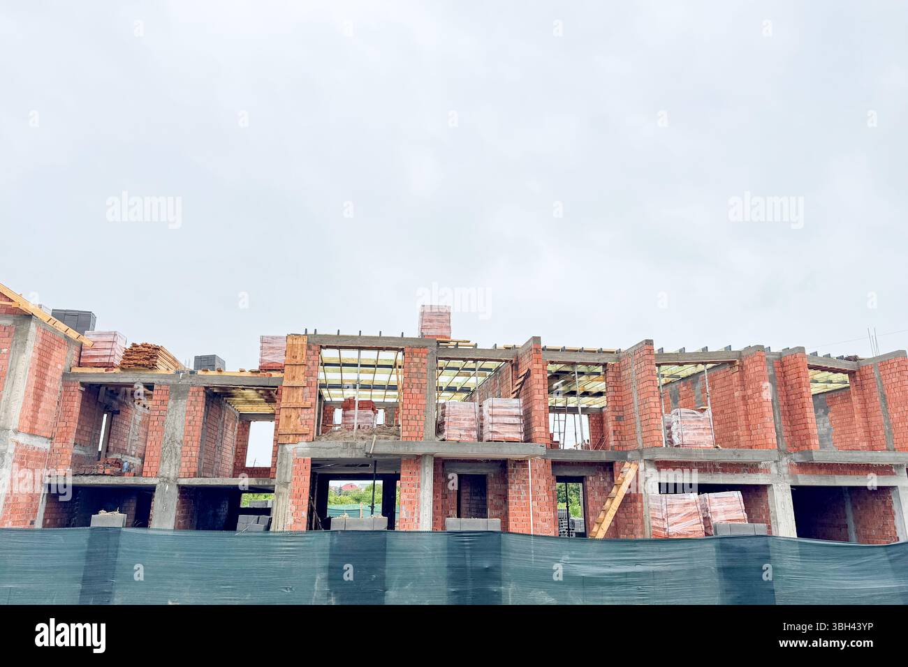 A partially constructed brick house stands with exposed wooden beams ...