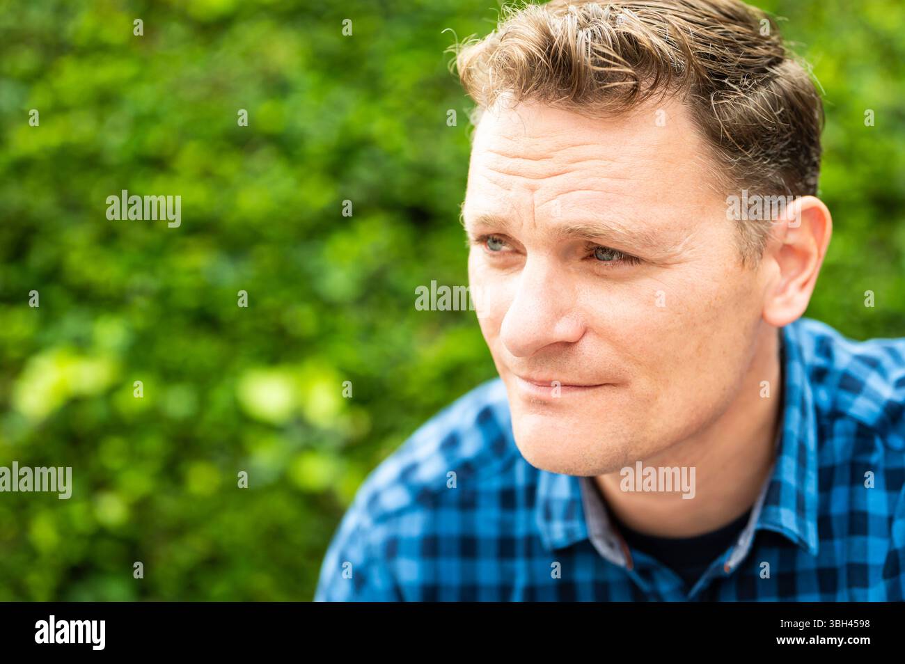 Outdoor portrait of a 46 yo white man wearing a checkered blue shirt ...