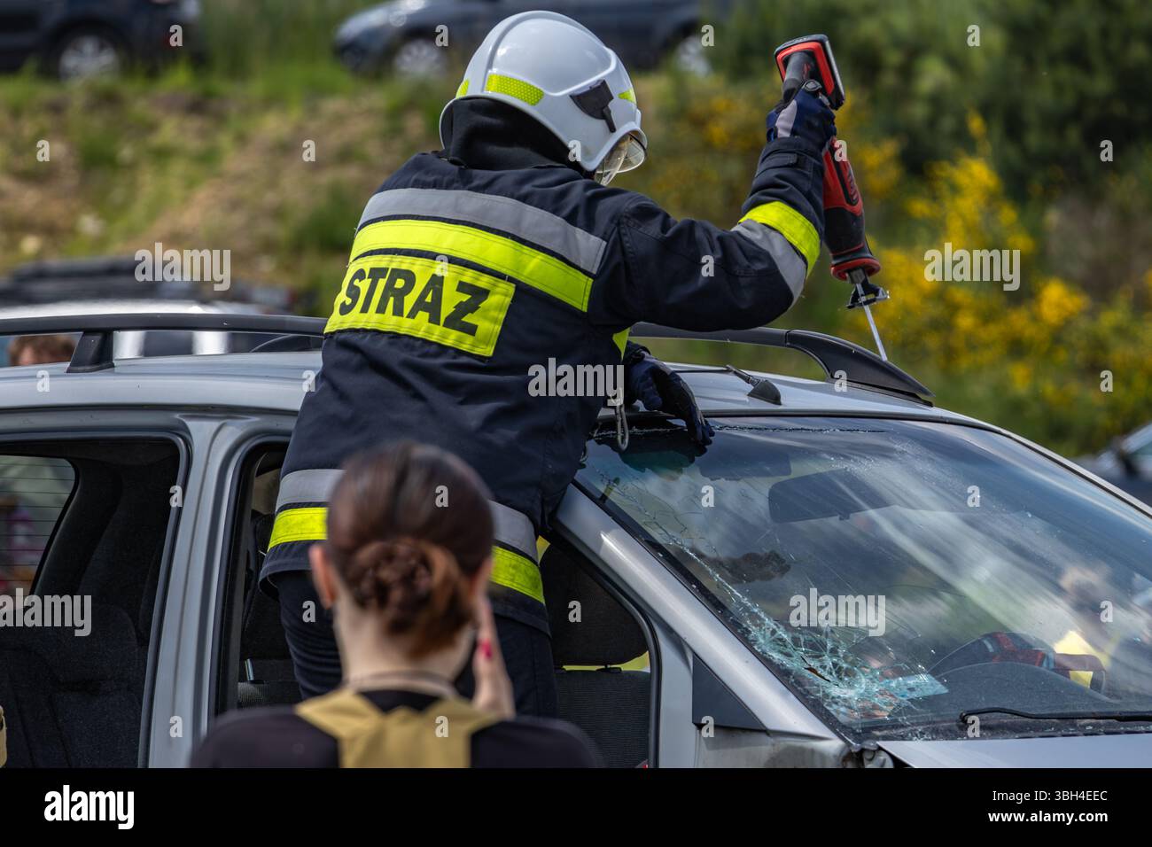 A firefighter from the rescue team cuts out a car windshield ...