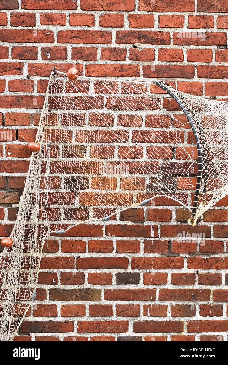 Old fish trap (fyke net) in front of a red brick wall – traditional ...