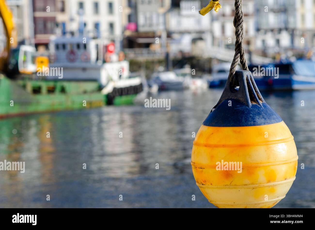 Bright yellow buoy hanging over calm marina water, capturing the ...