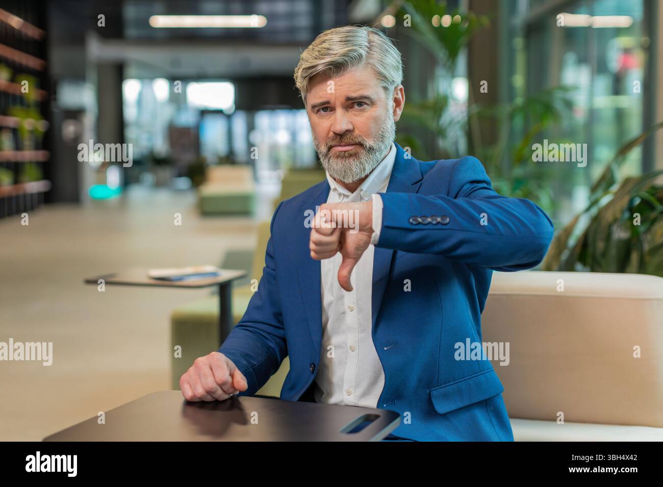 Dislike. Upset businessman guy in suit sitting in office lobby showing ...