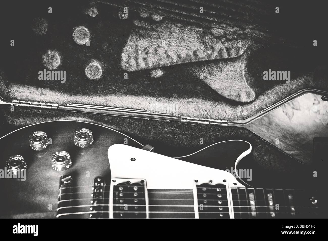 Black and white close-up of an electric guitar laying inside a guitar ...