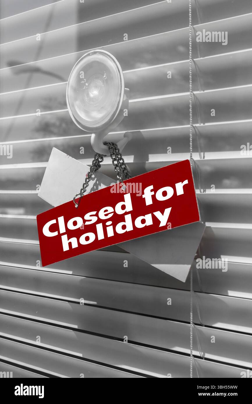 Sign saying Closed for holiday on a glass door with a white, closed ...