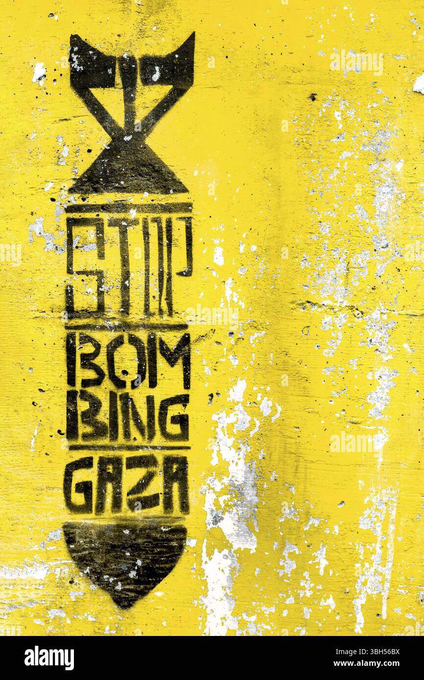 Graffiti on the yellow grungy wall depicting the silhouette of a bomb ...