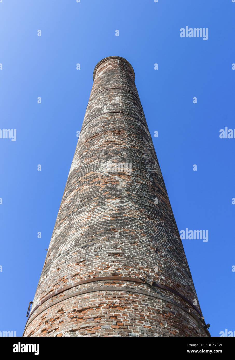 Bottom view of the old brick chimney isolated on a blue sky background ...