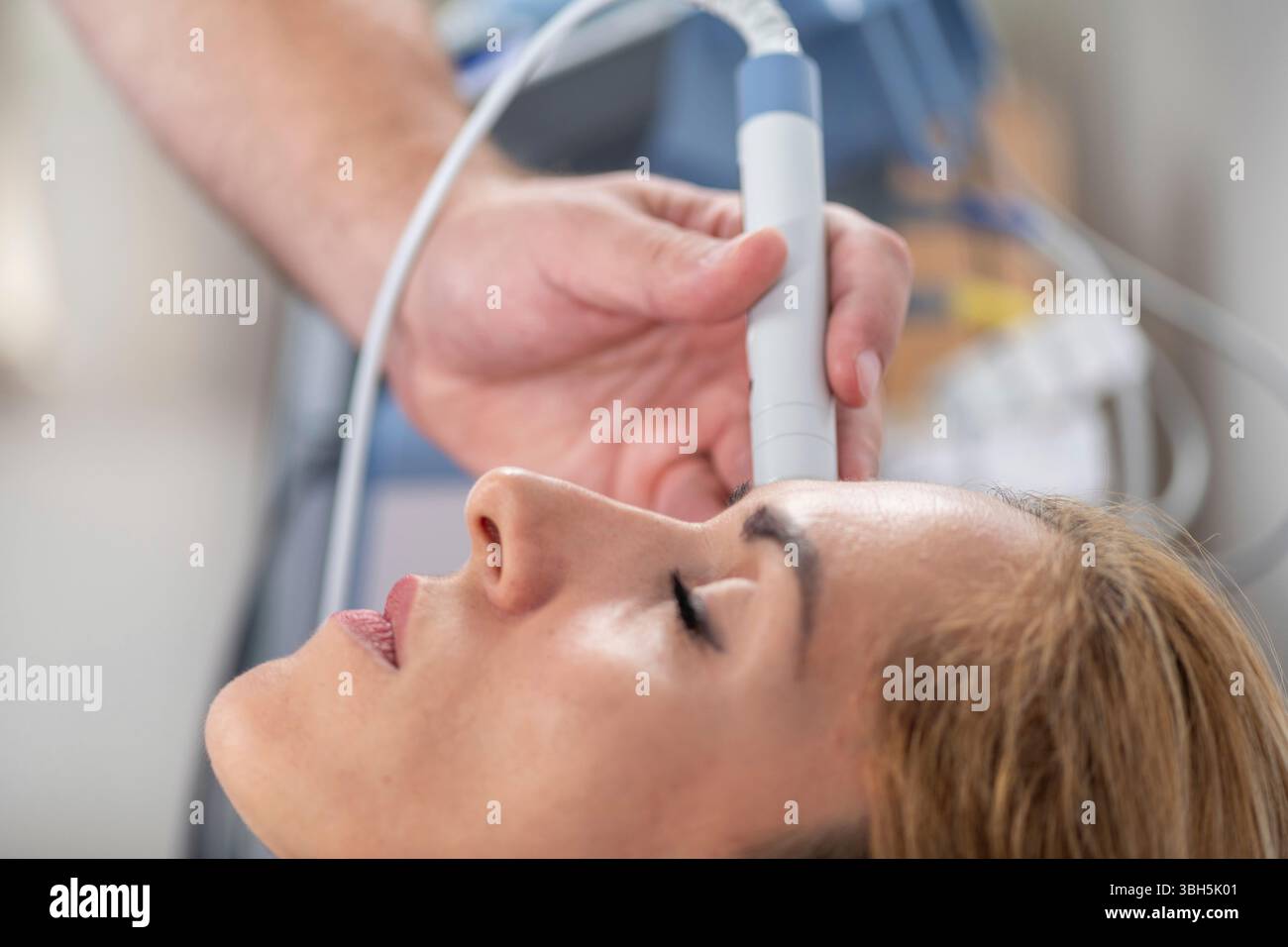 Physical therapist performs laser therapy on a patients sinus area to ...