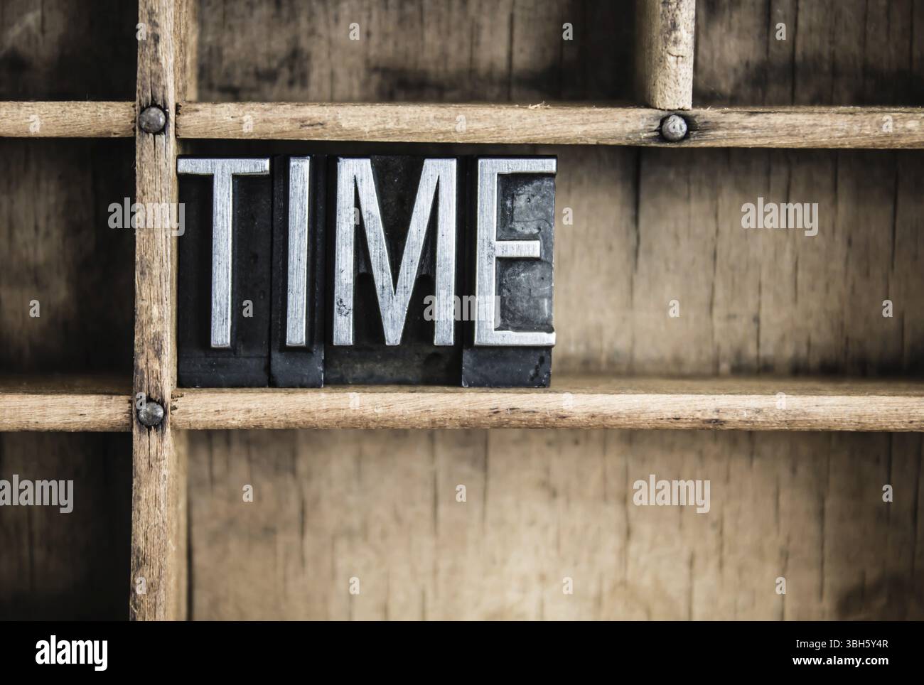 The word TIME written in vintage metal letterpress type in a wooden ...
