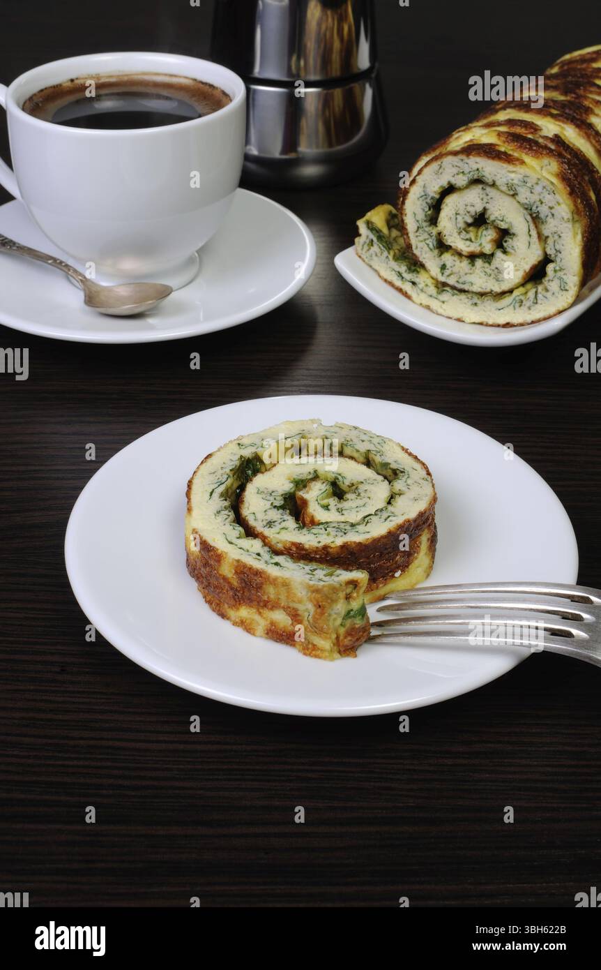 Slice of omelette with herbs and a cup of black coffee on the table ...