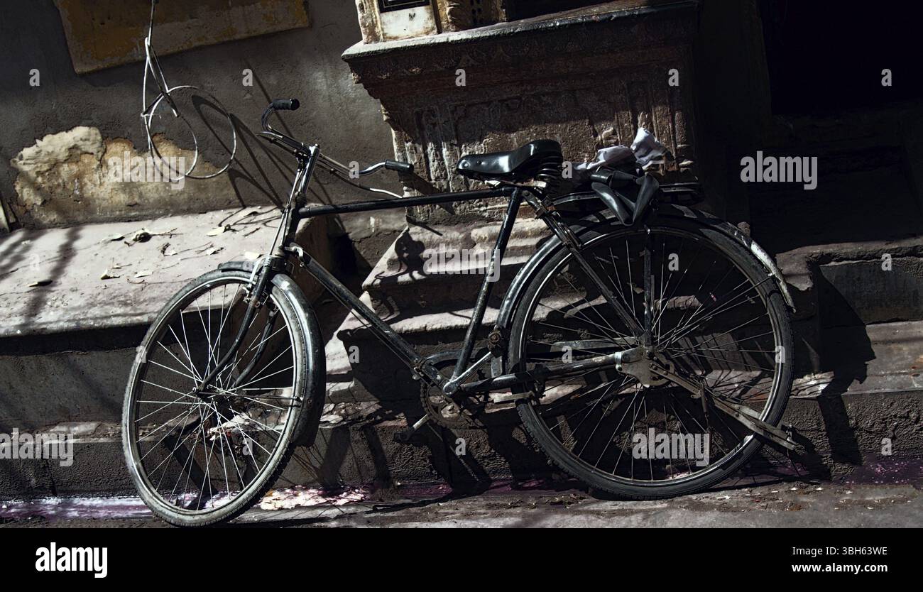 Black bike at steps of village house, with support footboard (stanchion, upright) on wheel Stock ...