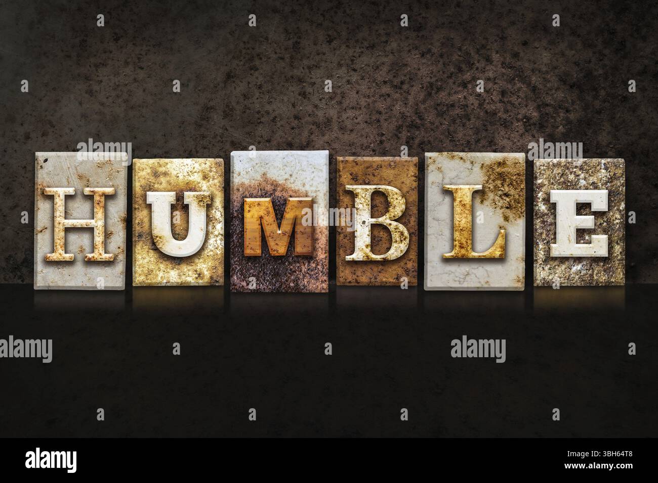 The word HUMBLE written in rusty metal letterpress type on a dark ...
