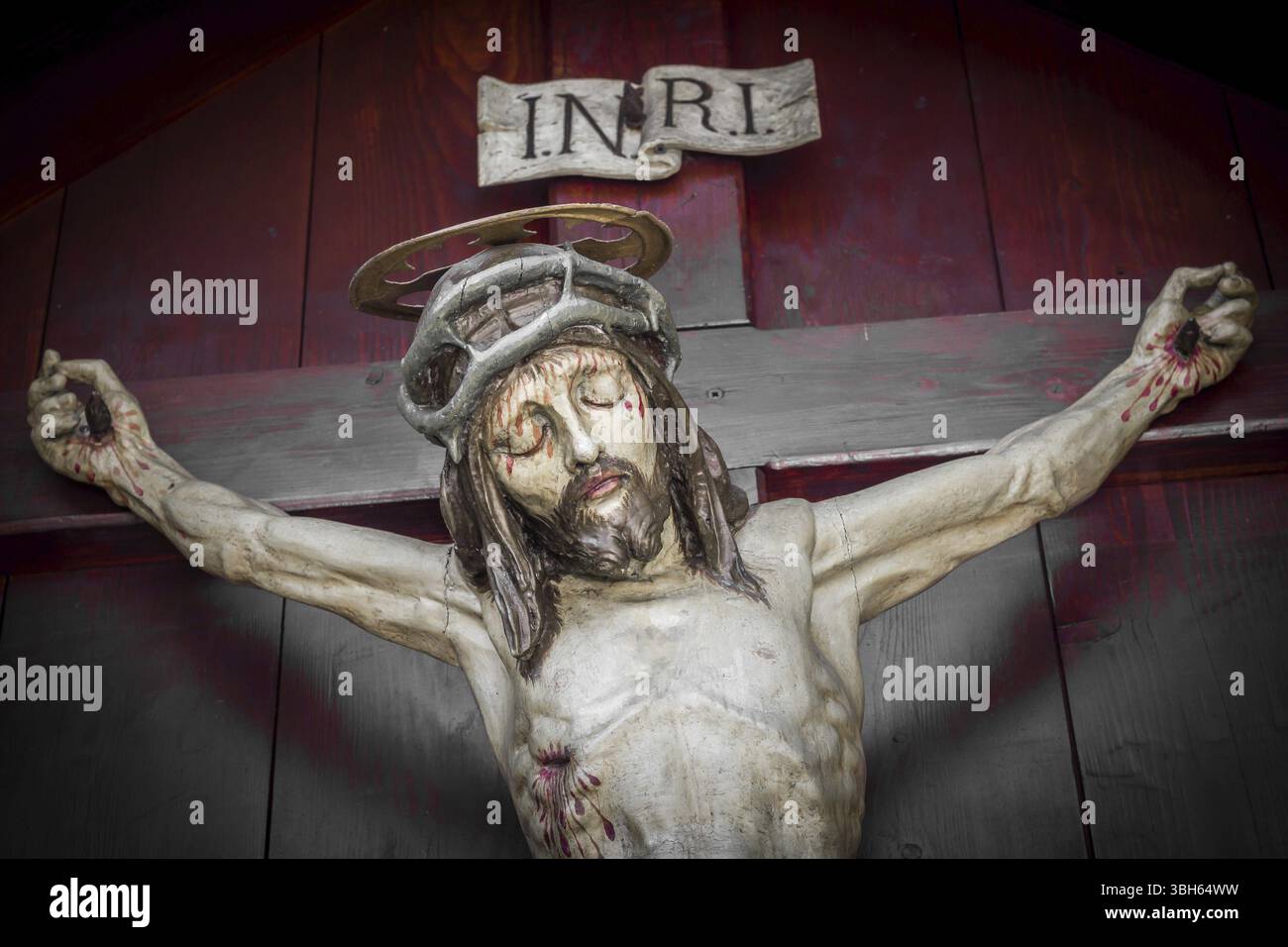 The bleeding body of Jesus Christ, crucified on a wooden cross. Shallow ...