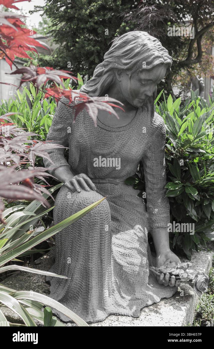 Statue at the cemetery. The representation of a girl who, bent over the ...