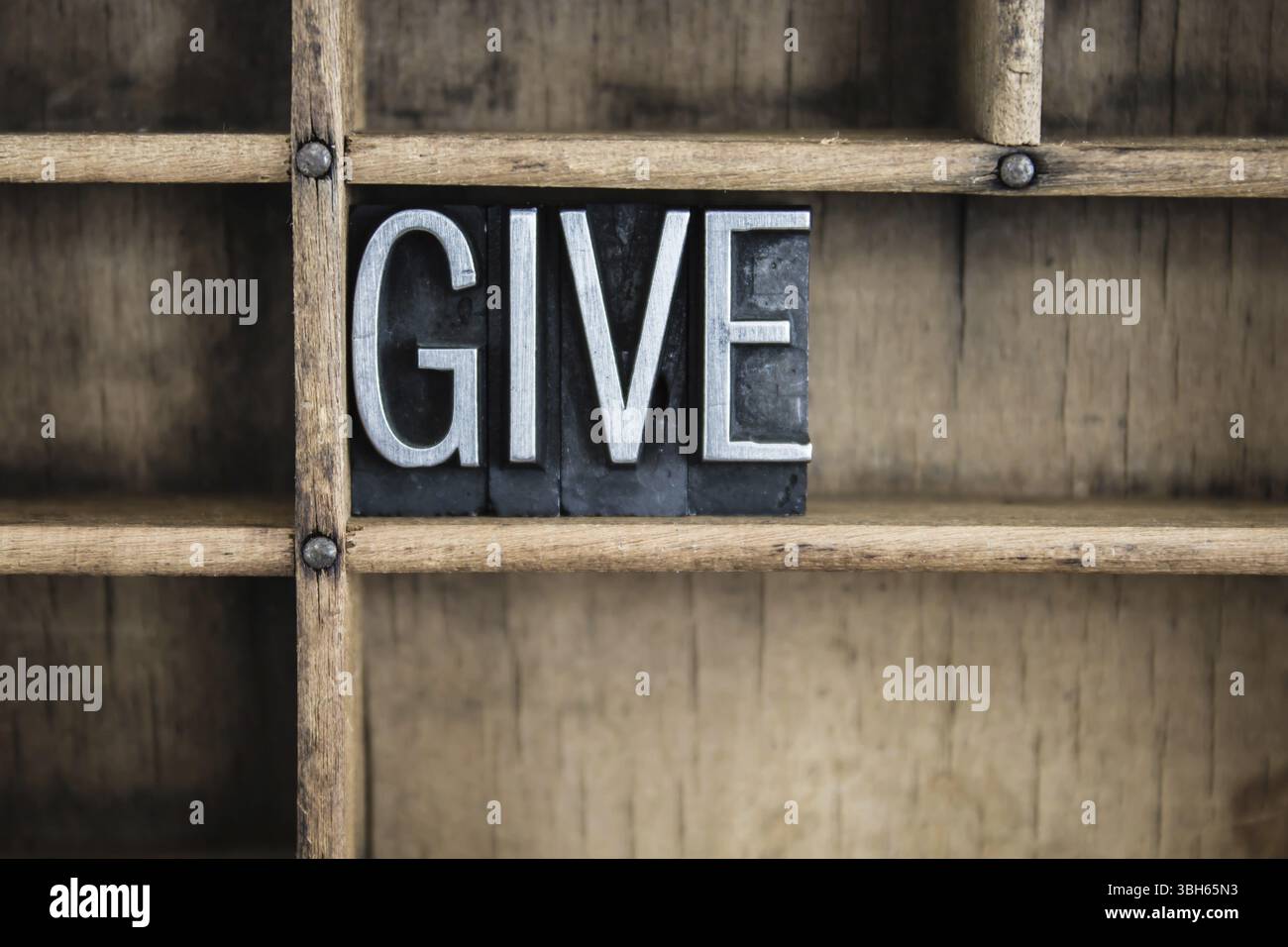 The word GIVE written in vintage metal letterpress type in a wooden ...