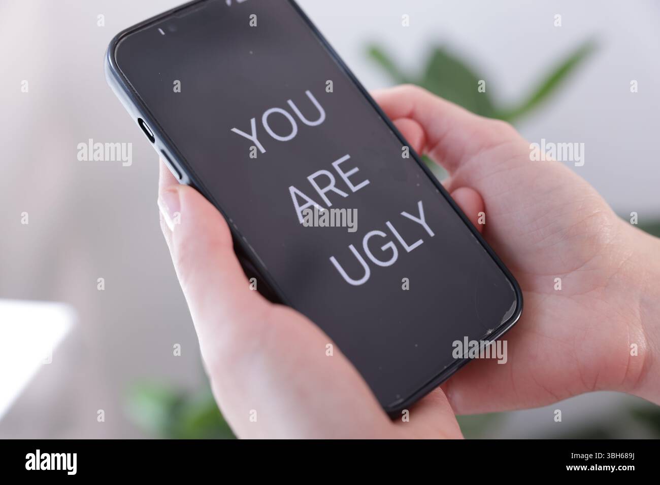 Cyber bullying. Woman holding smartphone with text You Are Ugly on ...