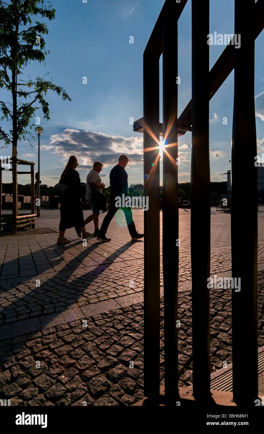 Long shadows and sun flare cast by pedestrians walking near Berlin’s Holocaust Memorial in early ...