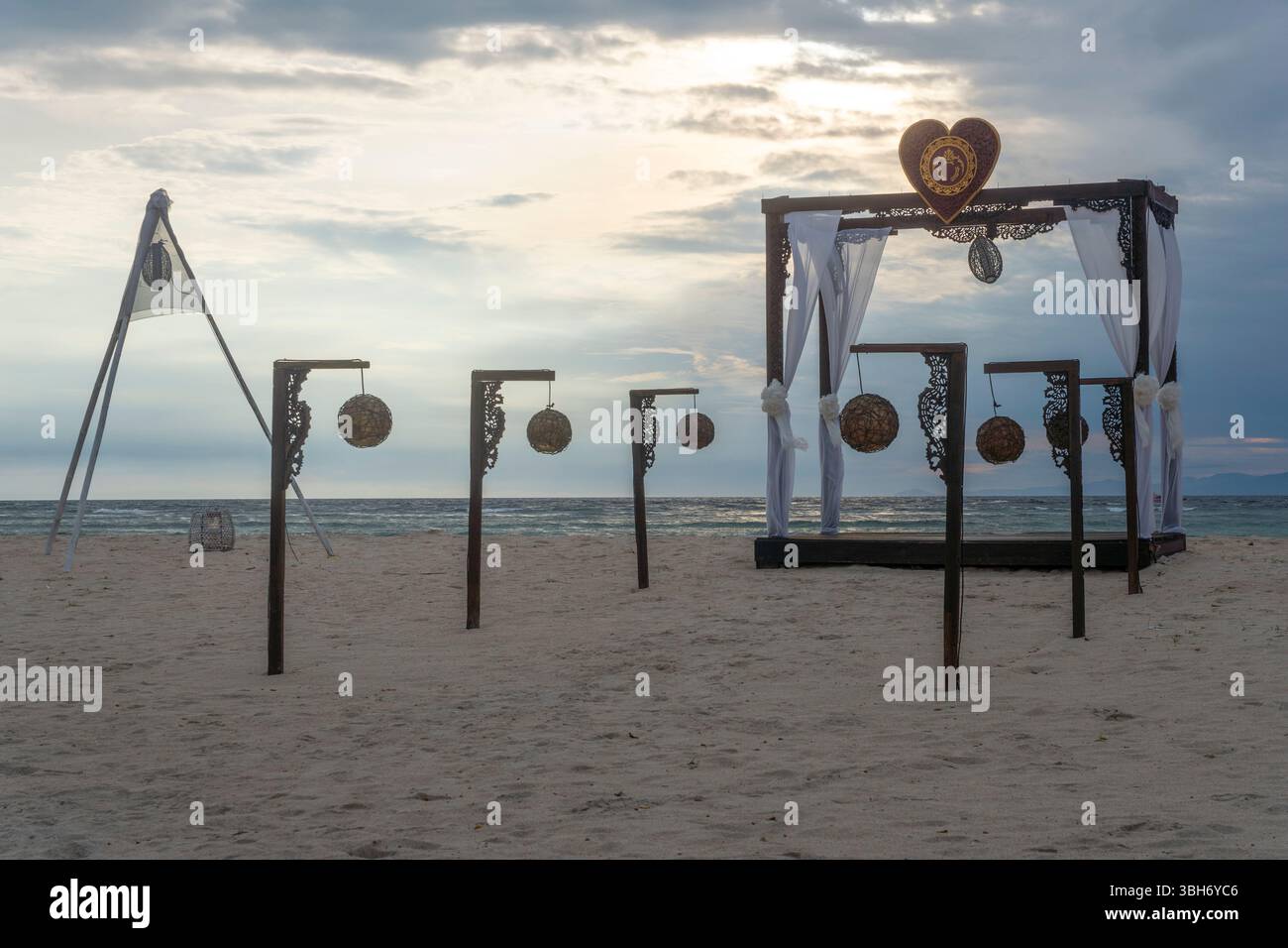 Beach scene with a pavilion and a few hanging lanterns. The pavilion is ...