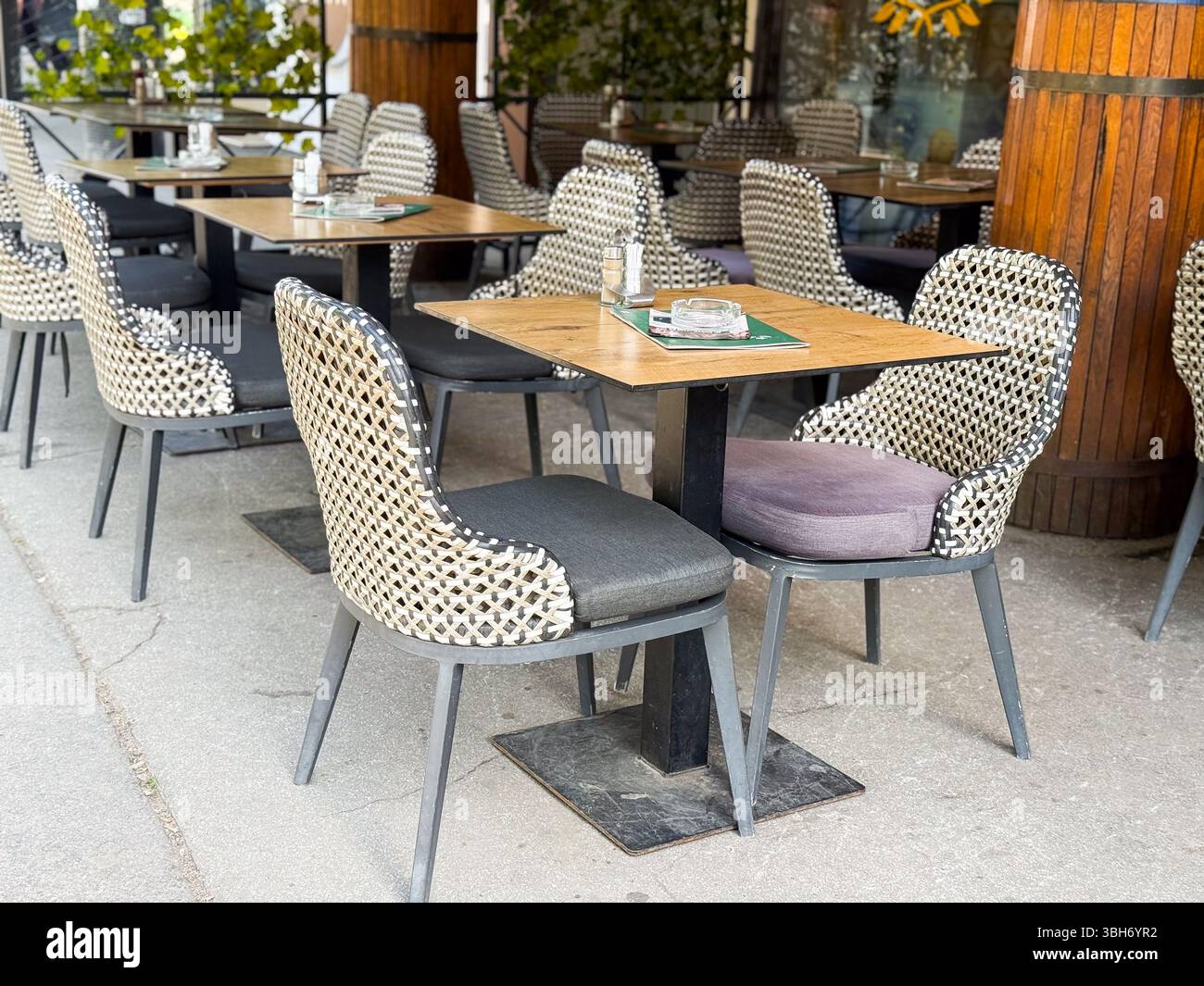 Outdoor restaurant seating with woven chairs and wooden tables ...