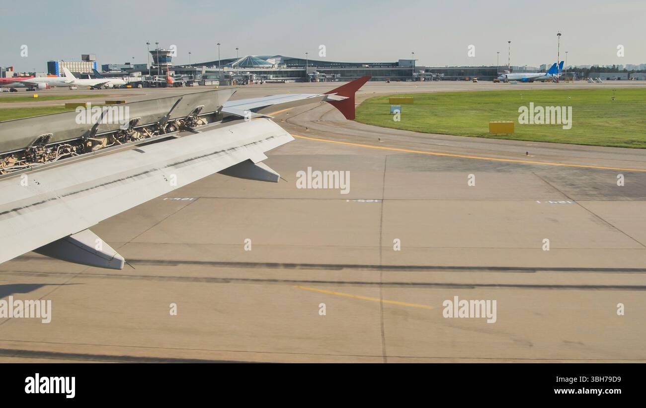 Airplane wing with open flaps approaching airport terminal Stock Photo ...