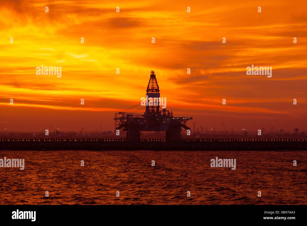 Offshore oil rig moored to the port pier at red sunset at dusk Stock ...