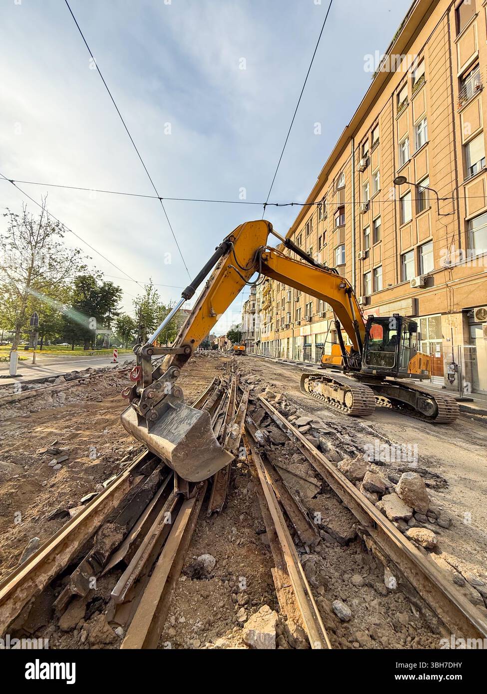 Excavator removing old tram rails at sunset. Urban transportation ...