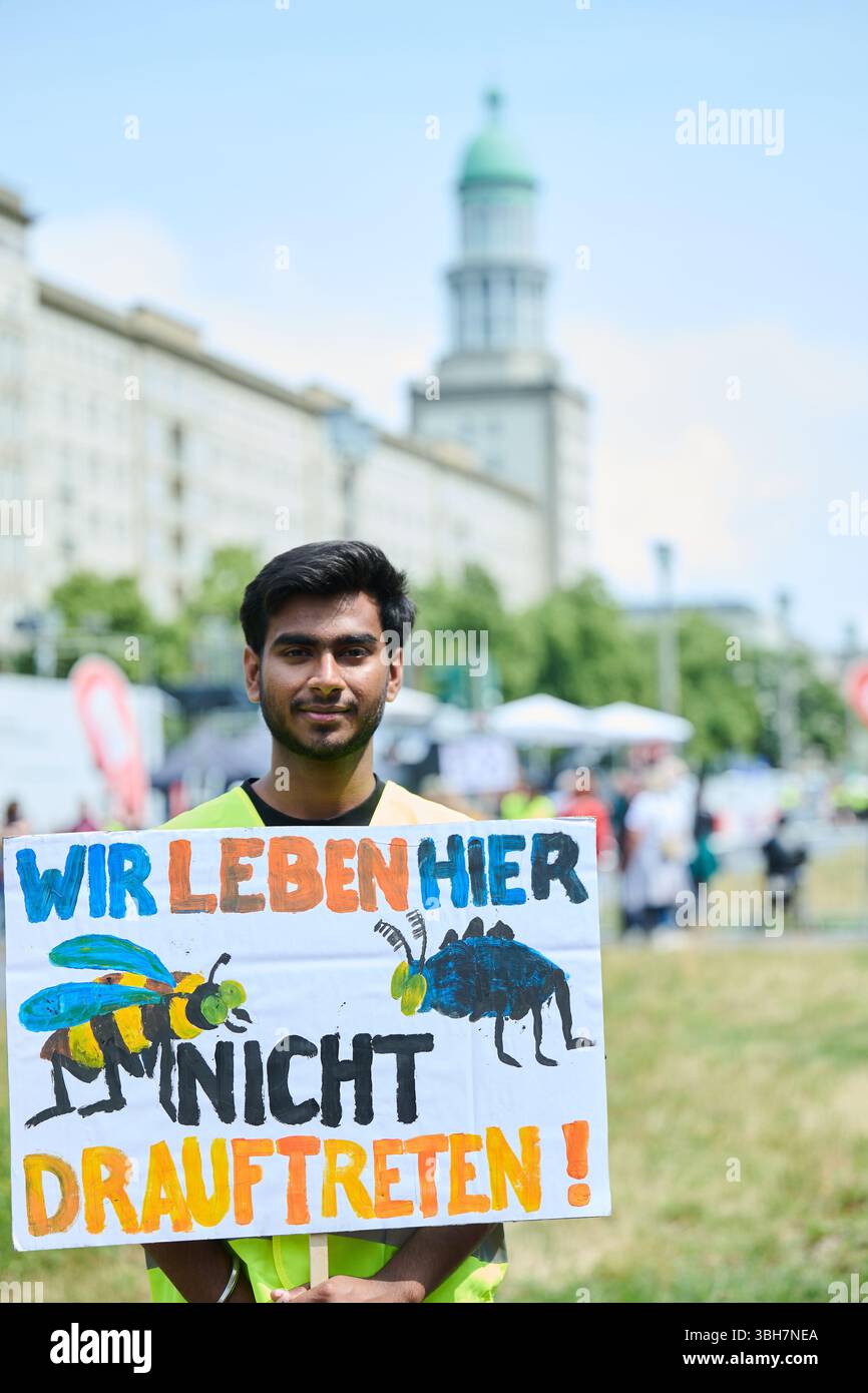 08 June 2025, Berlin: "We live here - don't step on it!" is written on a poster held by a man on ...