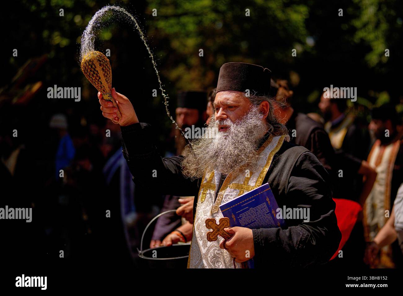 A priest sprinkles holy water during a religious procession, led by ...