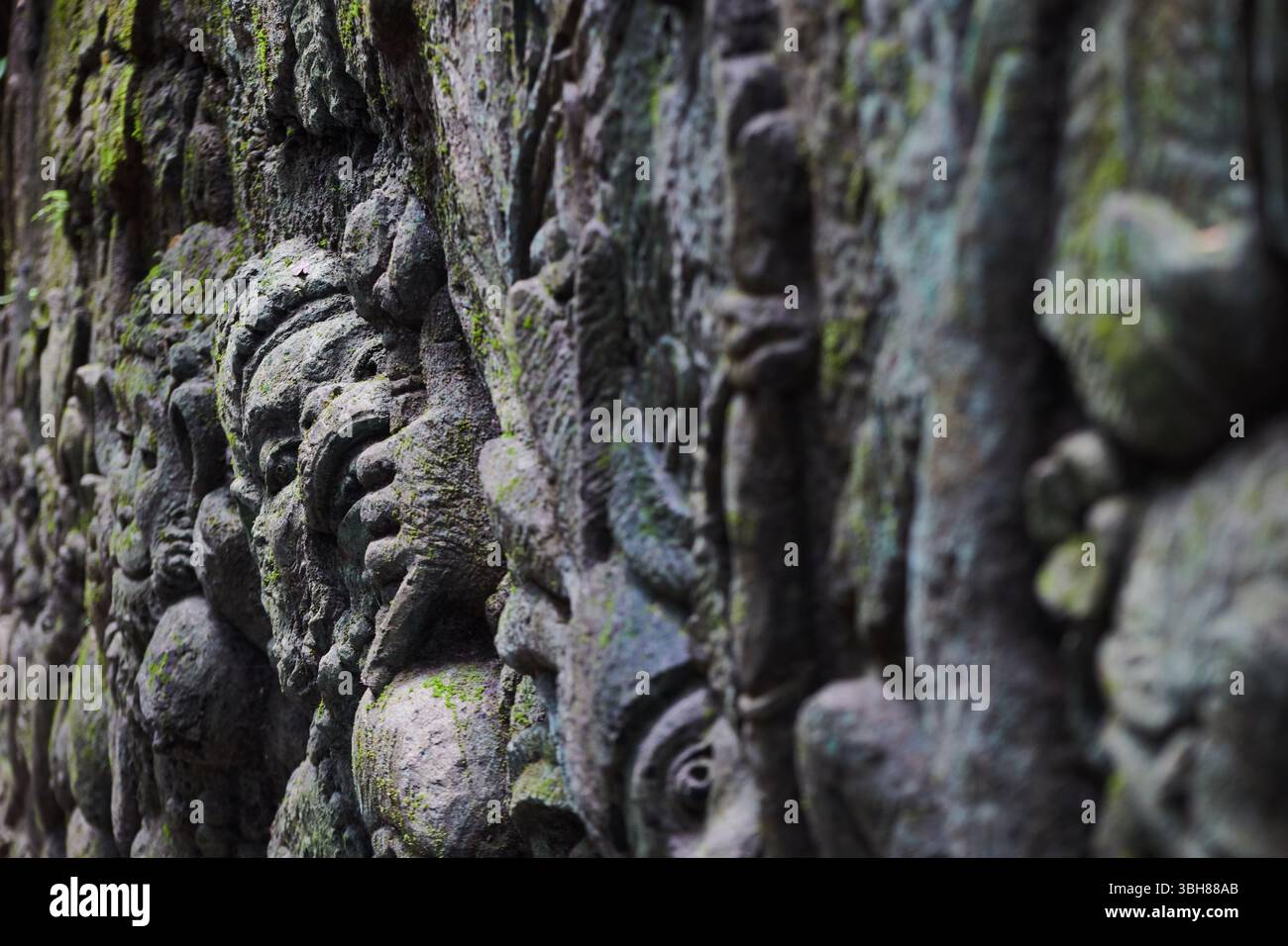 Stone carved feature of faces in Bali wall Stock Photo - Alamy