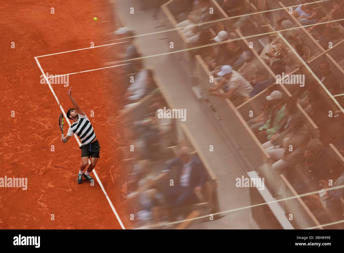 Spectators are reflected in a glass as Spain's Carlos Alcaraz serves ...