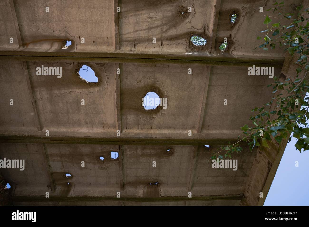 Old concrete ceiling with multiple holes and visible metal ...