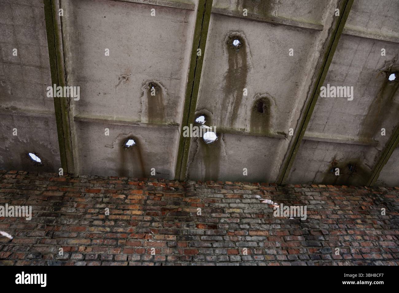 Old concrete ceiling with multiple holes and visible metal ...