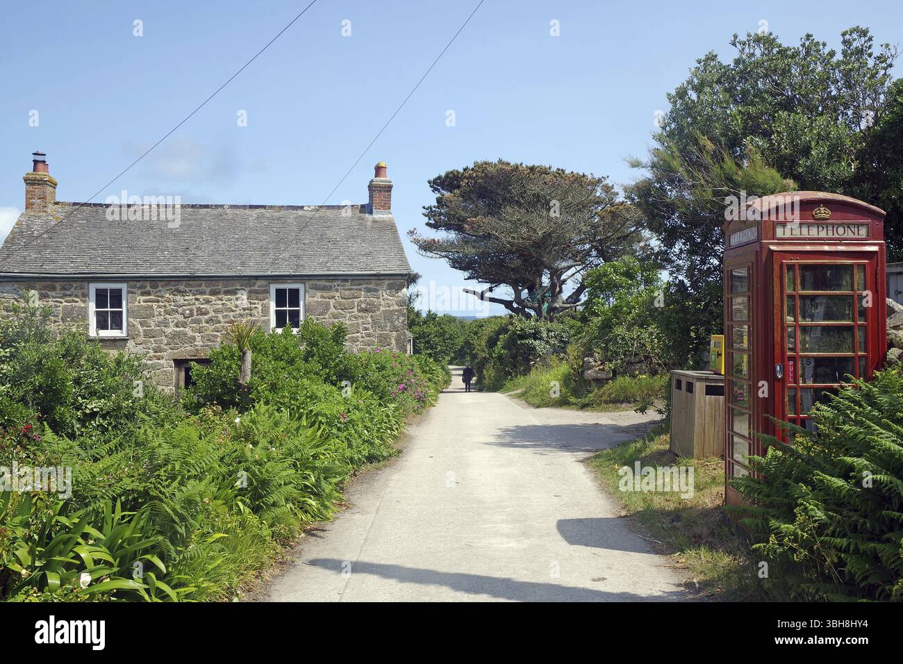 A rural scene with a stone house and red brtish telephone box along a ...