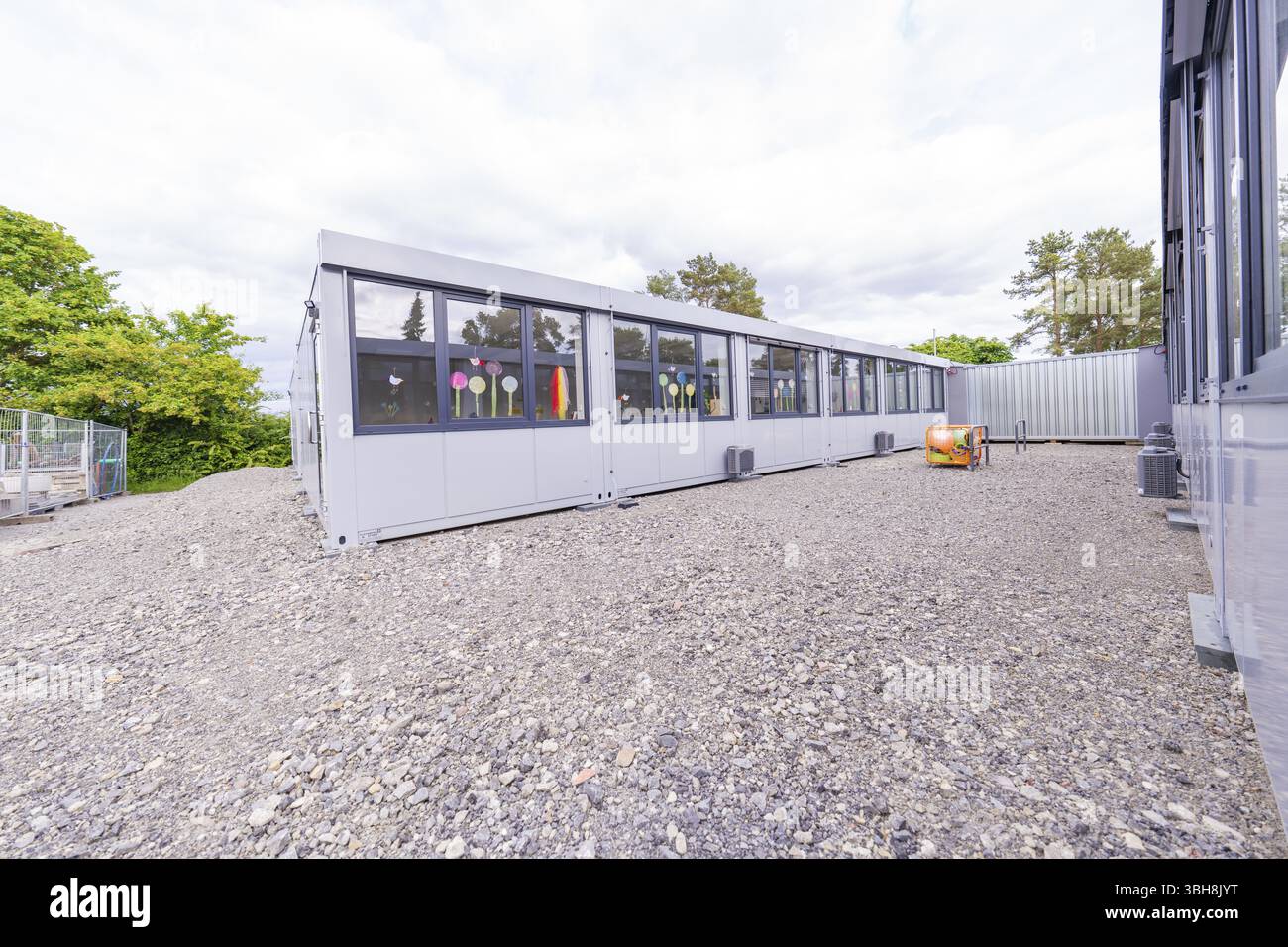 Elongated modern building with large windows and gravel floor ...