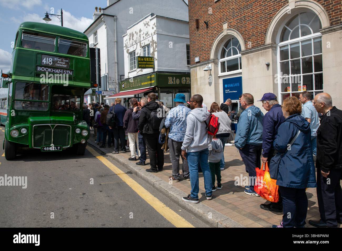 People wait in line to board a green heritage bus. Volunteers operating ...