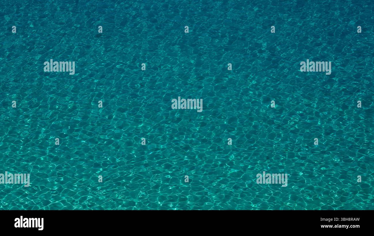 Transparent turquoise water surface gently rippling under the summer ...