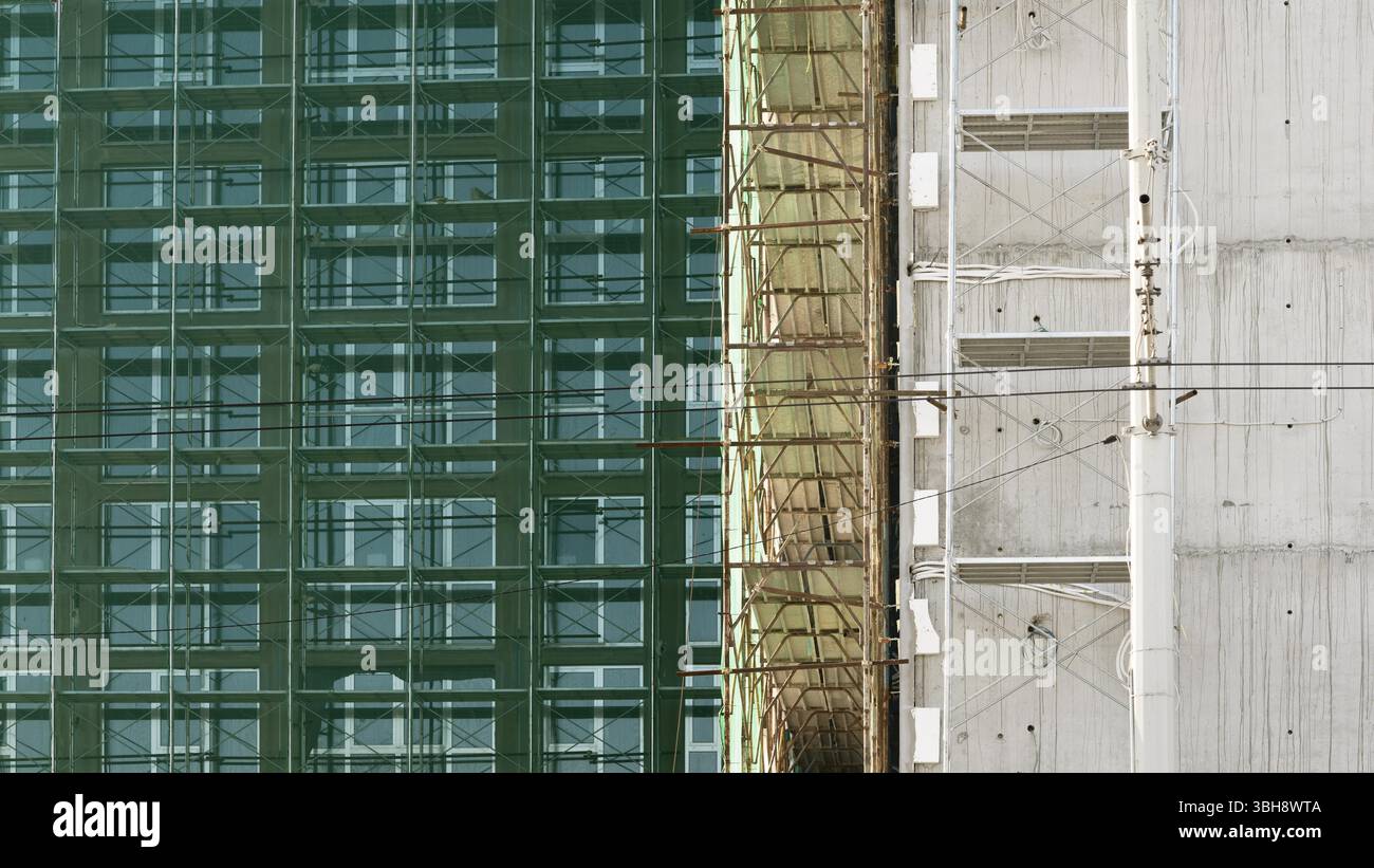 High-rise building under construction with green mesh safety netting ...