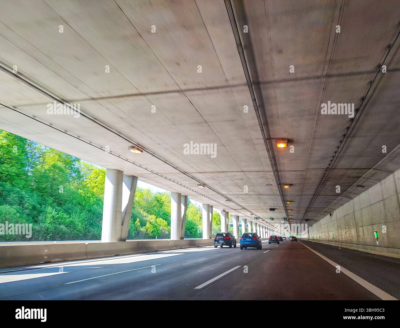 Vehicles navigate a multi-lane roadway approaching an innovative tunnel ...