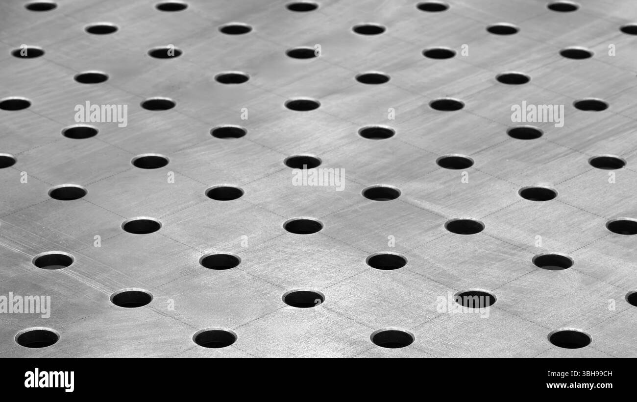 A close up of a metal surface with many small holes. The holes are ...