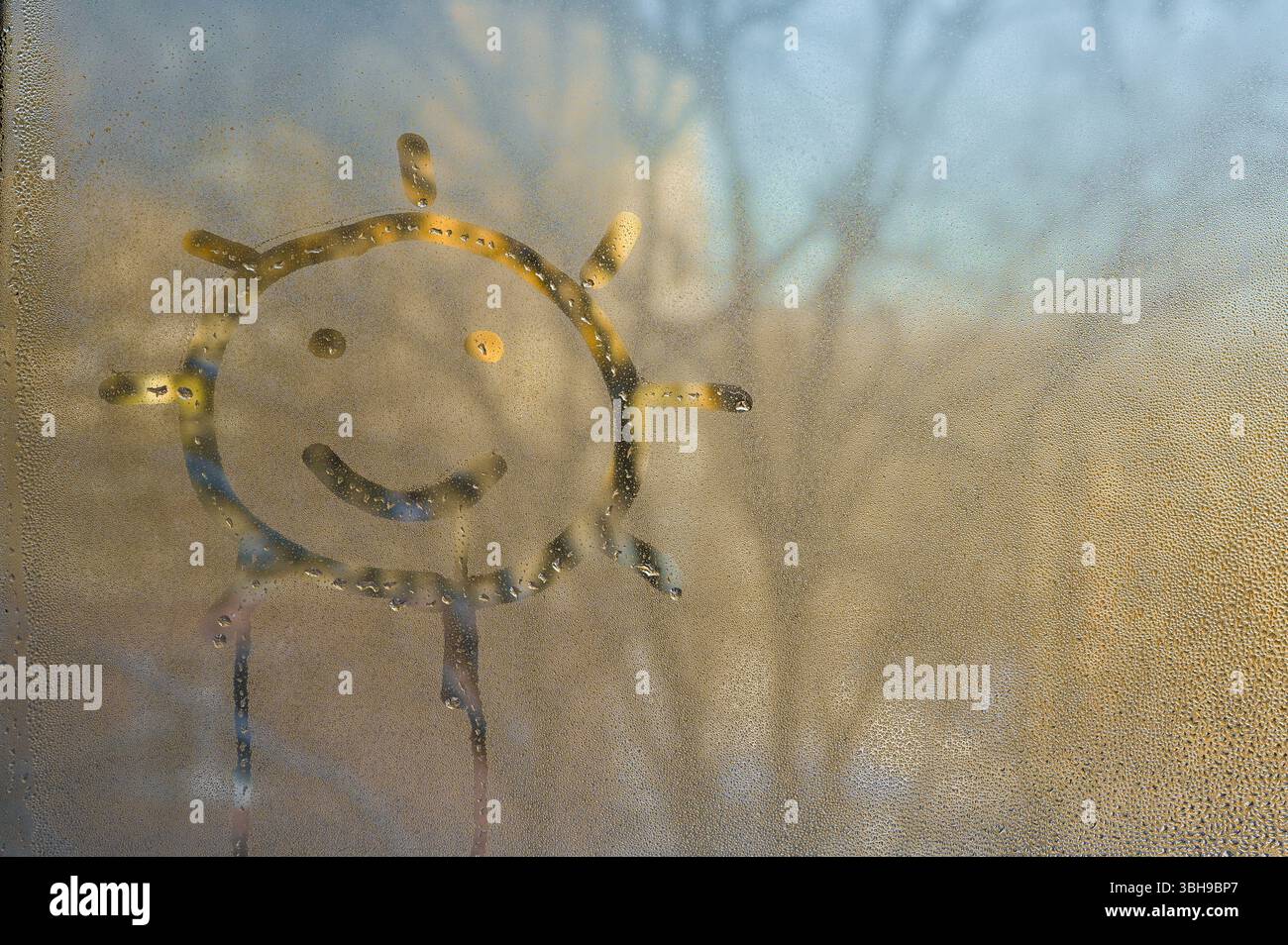 drawing of the sun on wet glass. Cheerful sun With smile painted on ...