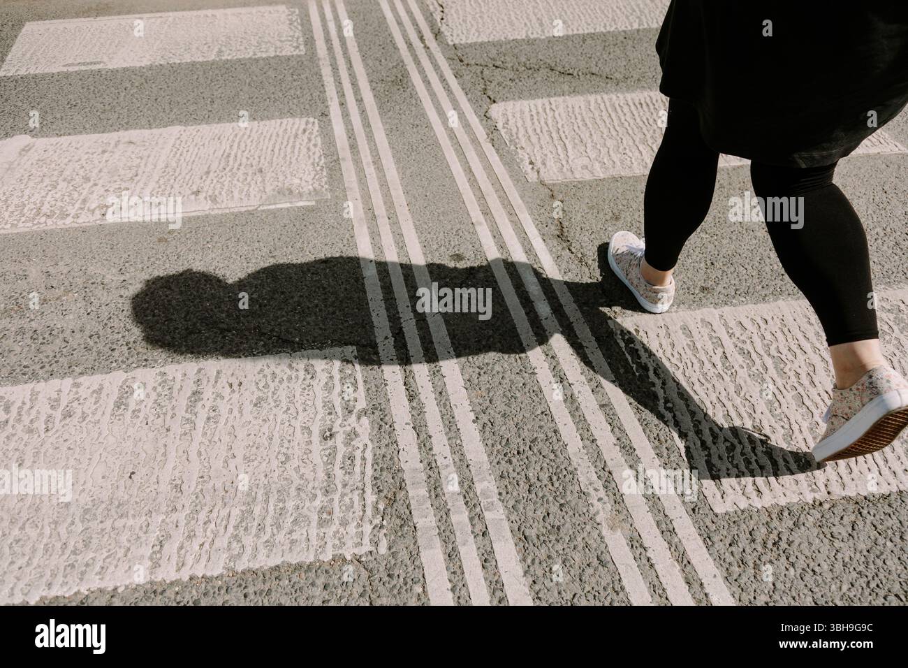 A woman confidently striding over a city crosswalk, captured from ...