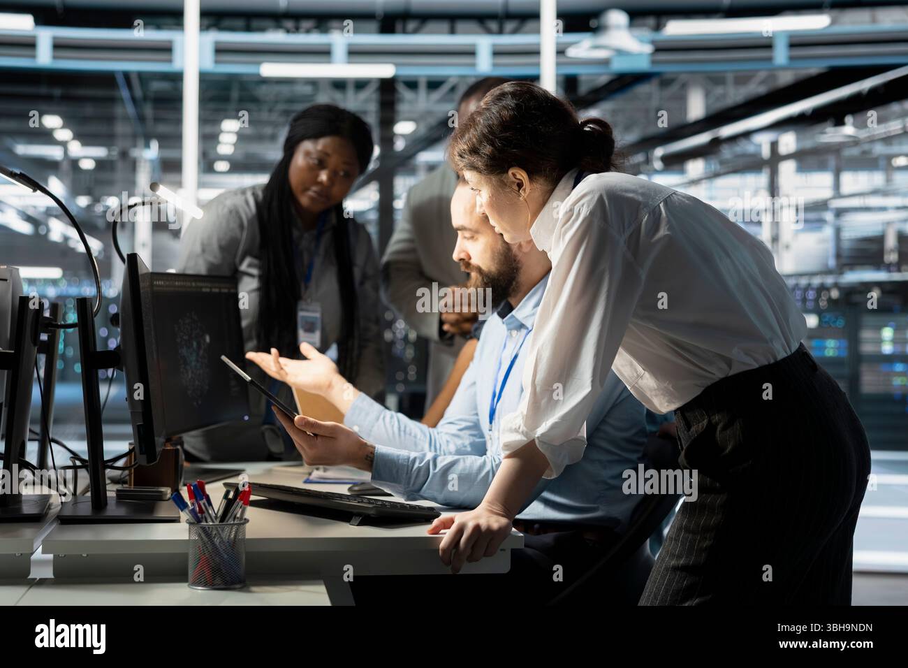 Data center engineering team doing brainstorming, monitoring system performance using computer ...