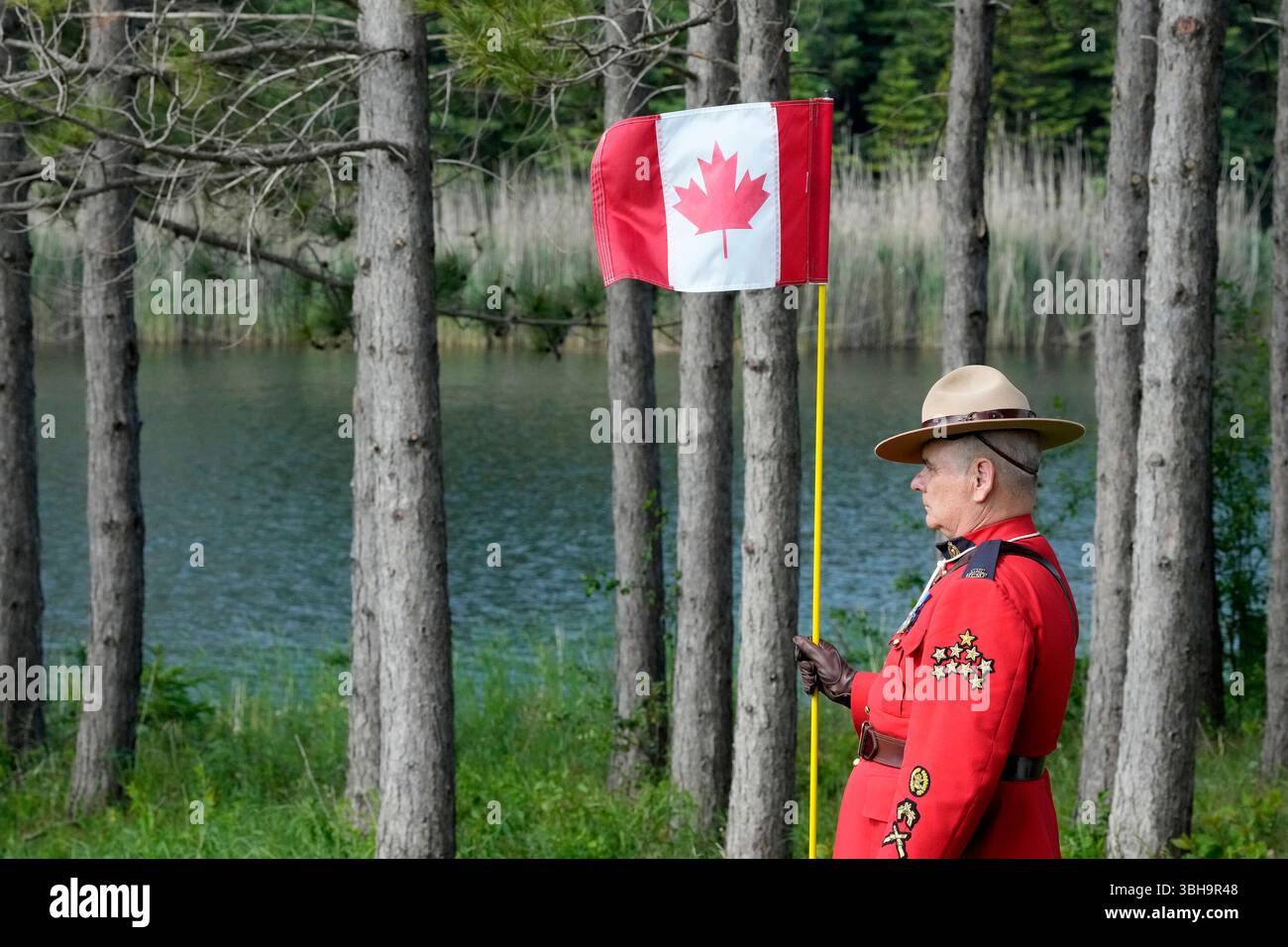 An RCMP officer on the 18th green holds a Canadian flag as players putt ...