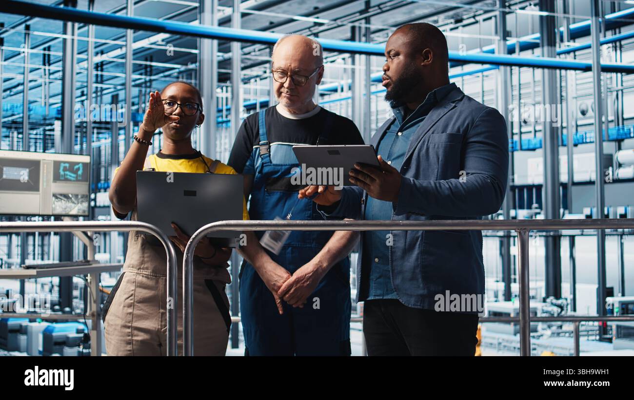 Engineers talking with manager overseeing smart factory, showing ...