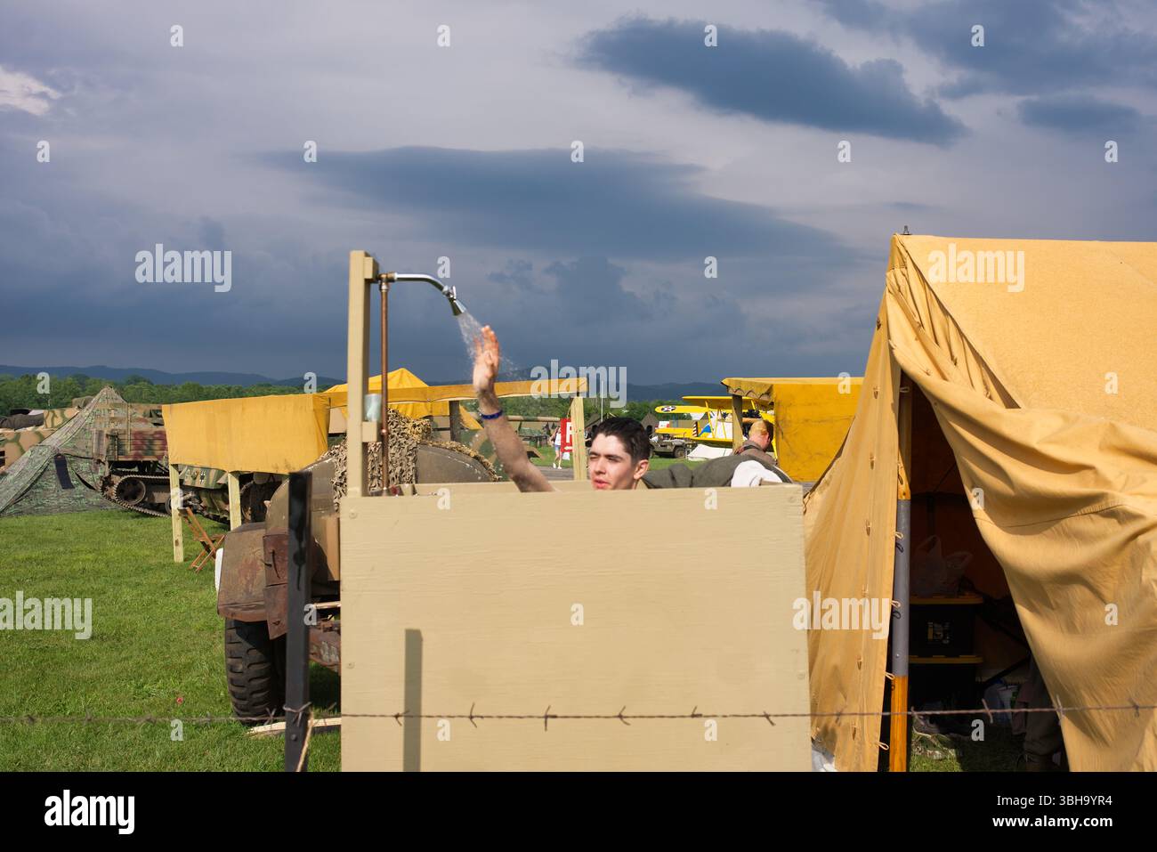 A young man washes himself at a makeshift outdoor shower constructed ...